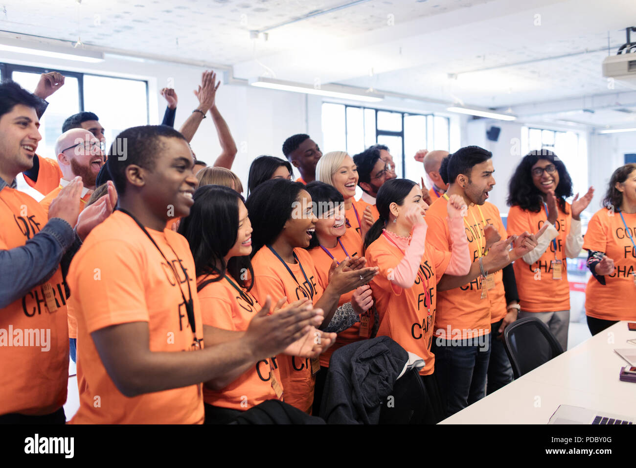 Happy hackers cheering and celebrating, coding for charity at hackathon ...