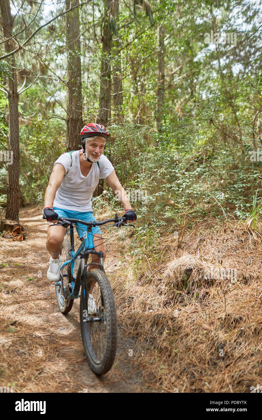 Mature man mountain biking on trail in woods Stock Photo - Alamy