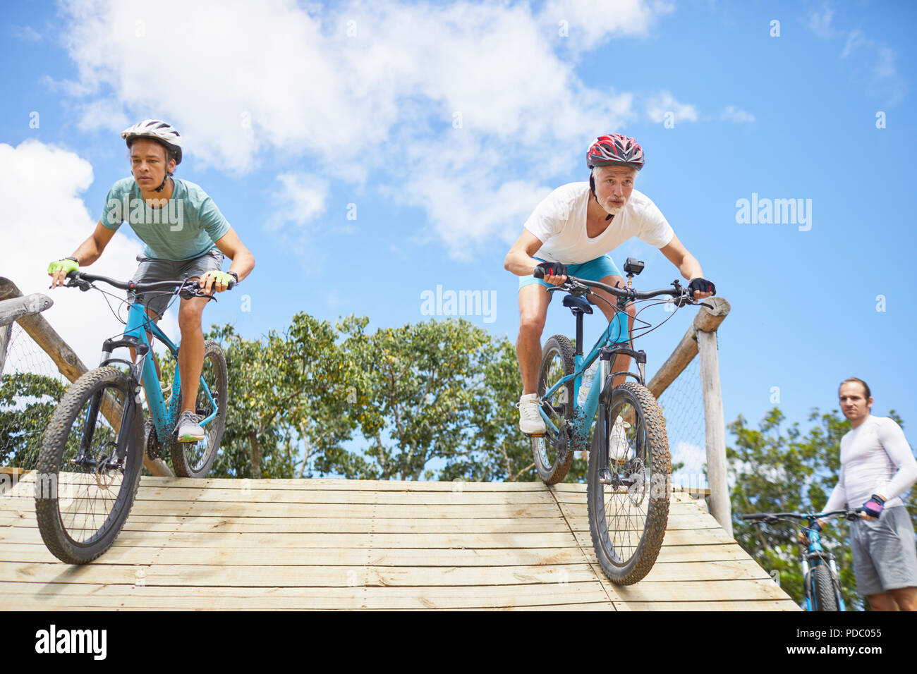 Focused men mountain biking on obstacle course ramp Stock Photo - Alamy