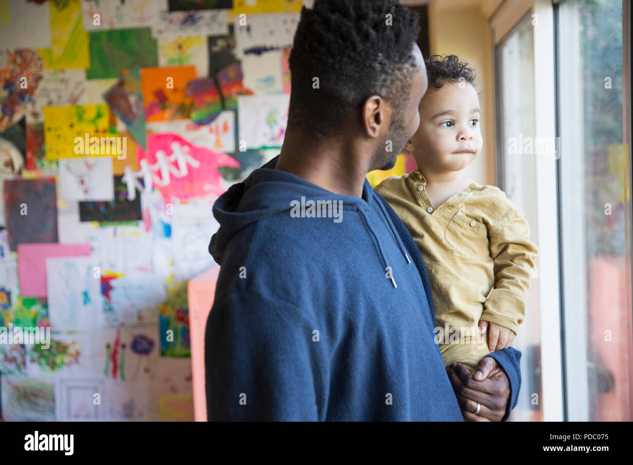 Father holding curious, innocent baby son looking out window Stock ...