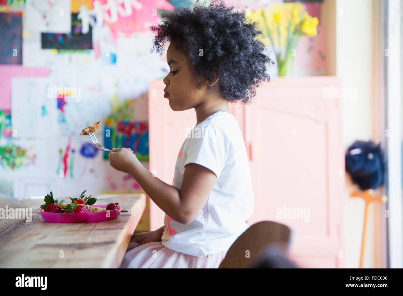 Curious girl eating breakfast at table Stock Photo - Alamy