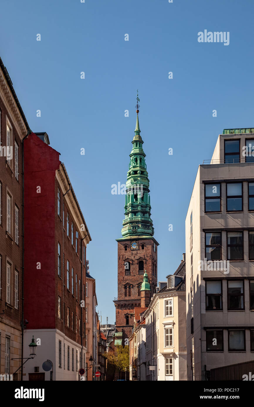 old tower with tall spire and historical buildings on street in ...