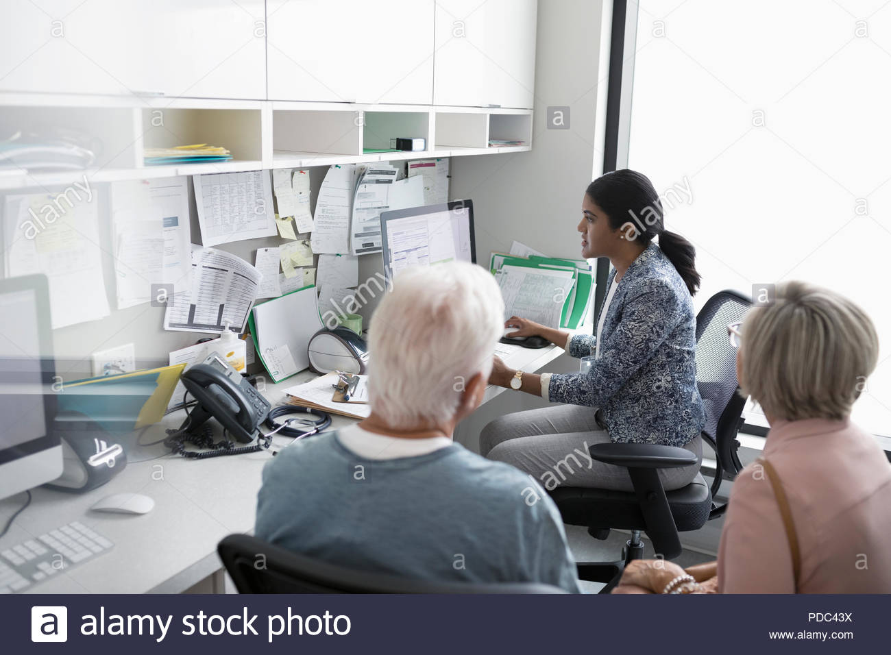 Senior couple watching doctor using computer in clinic office Stock ...