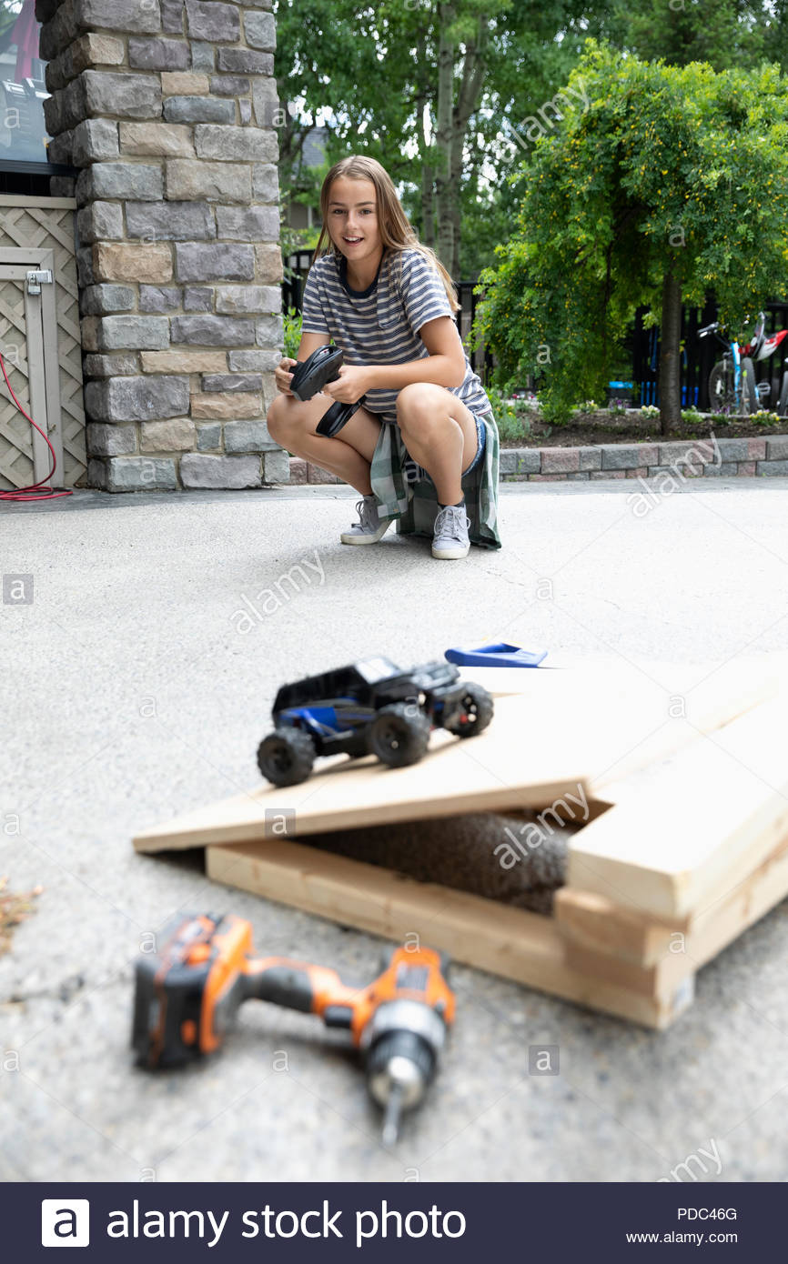 Tween girl playing with remote controlled car and ramp in driveway ...