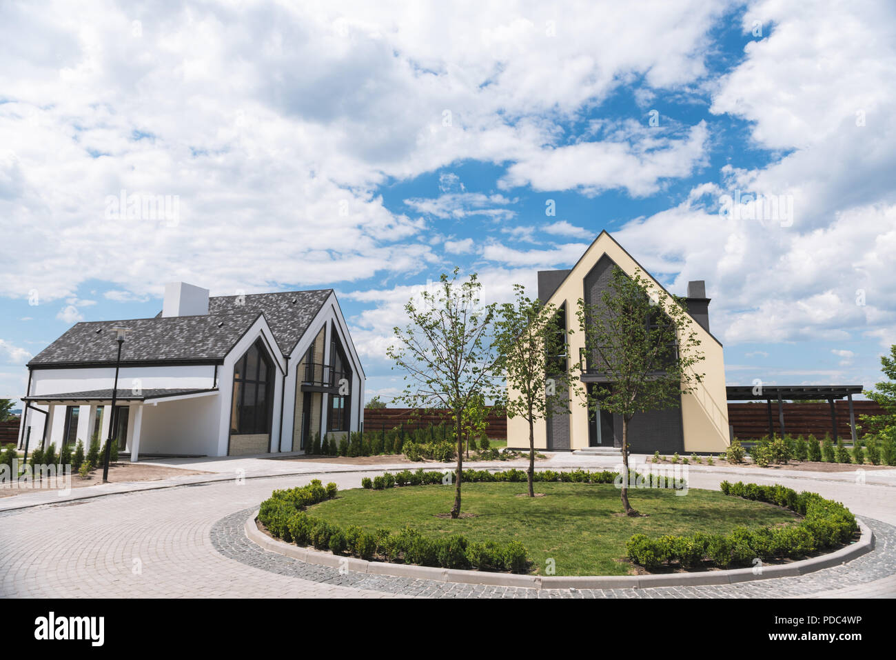 Three young trees growing in front of the buildings Stock Photo - Alamy