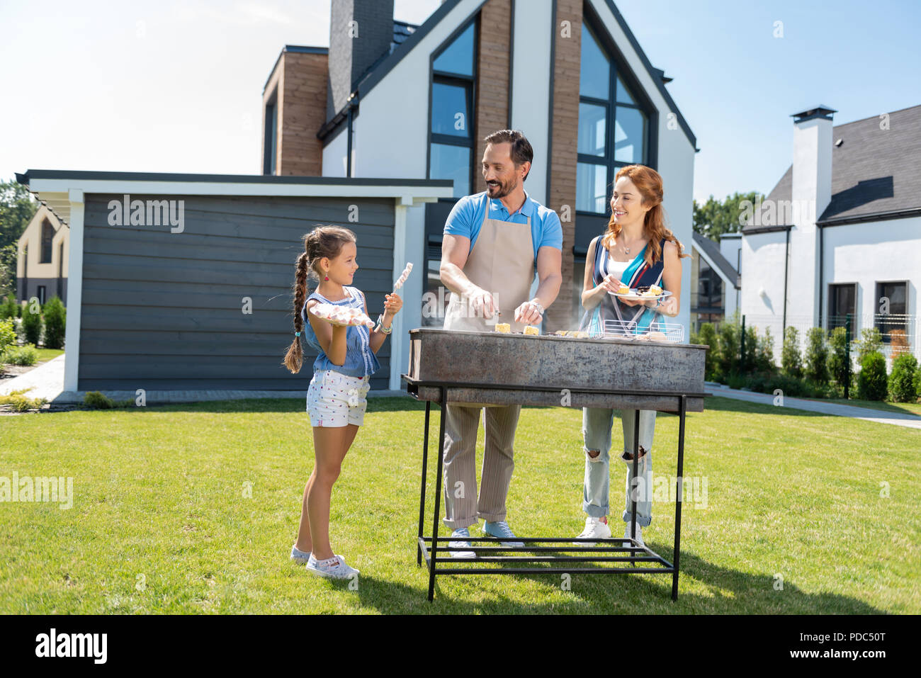 Positive joyful parents looking at their daughter Stock Photo - Alamy