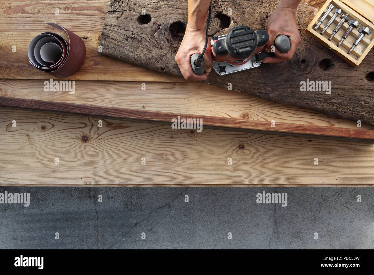 hands carpenter working a wooden rustic old board with a milling router ...