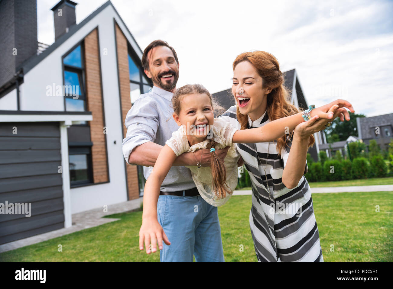Positive nice parents holding their daughter Stock Photo - Alamy