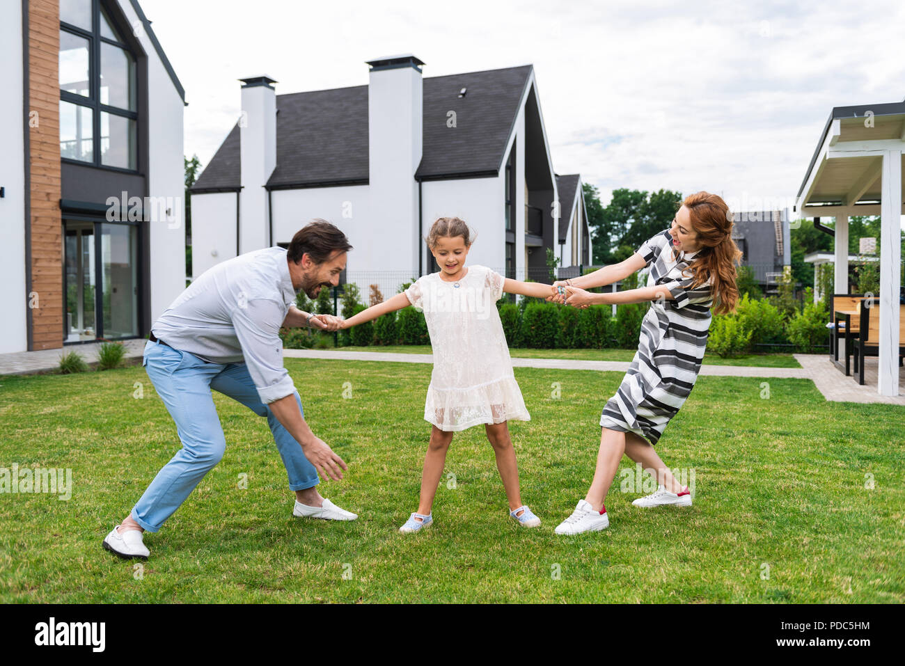 Pleasant cute girl standing between her parents Stock Photo - Alamy
