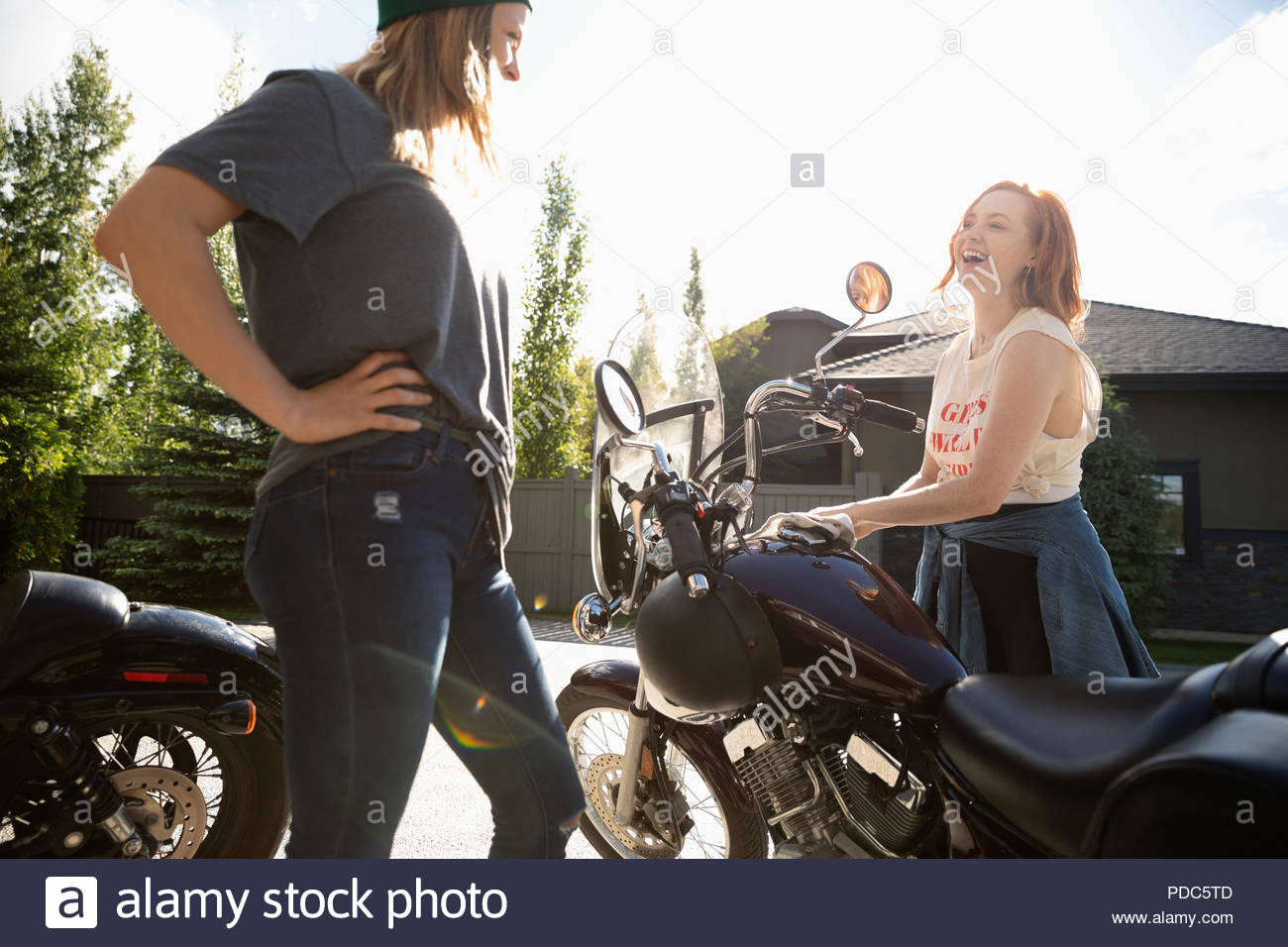 Young women friends with motorcycles in sunny driveway Stock Photo - Alamy