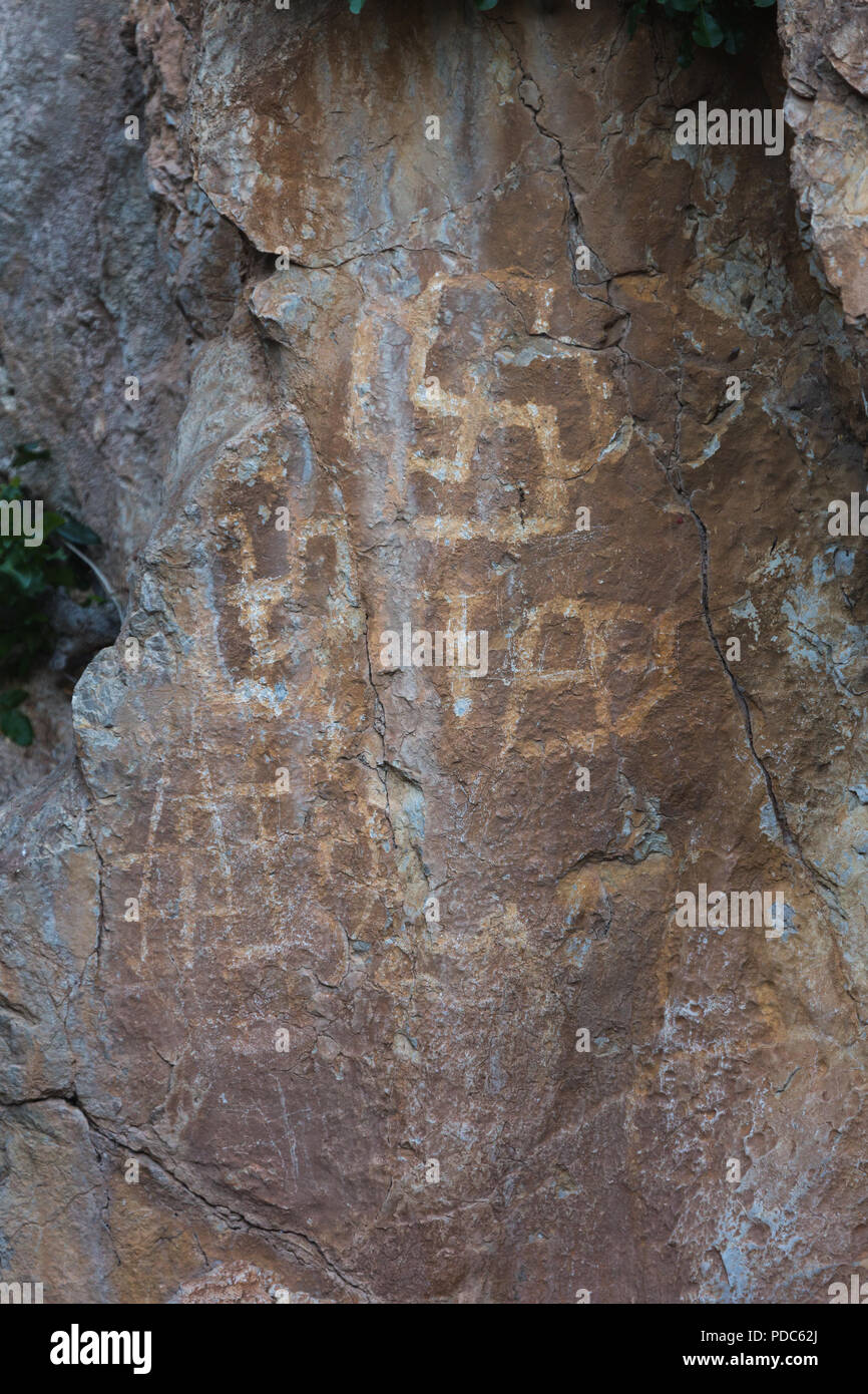 Ancient prehistoric archaeological rock drawings on cliff face of ...
