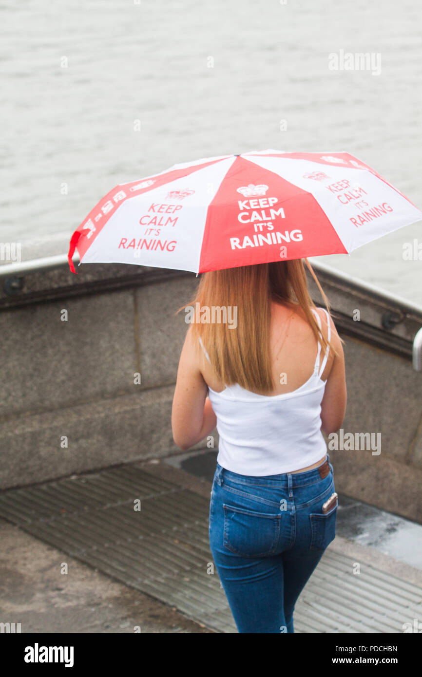 London UK. 9 August 2018. A pedestrian sheltering underneath an ...