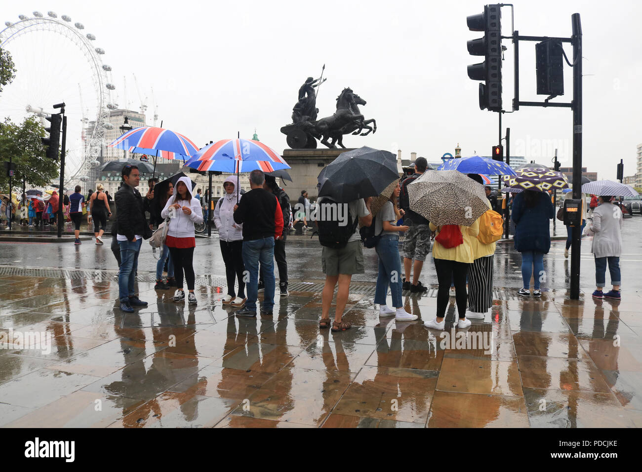 London UK. 9th August 2018. Pedestrians wearing ponchos and shelter ...