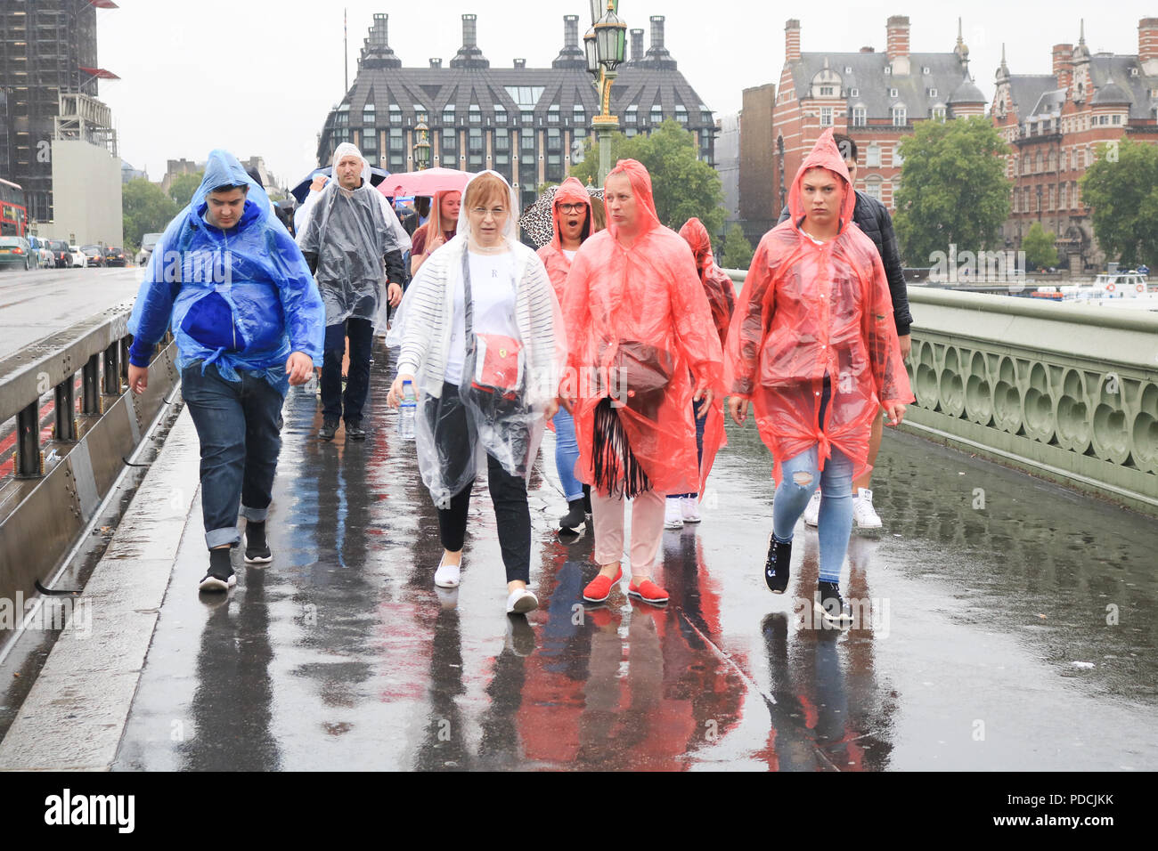 London UK. 9th August 2018. Pedestrians wearing ponchos sheltering from ...