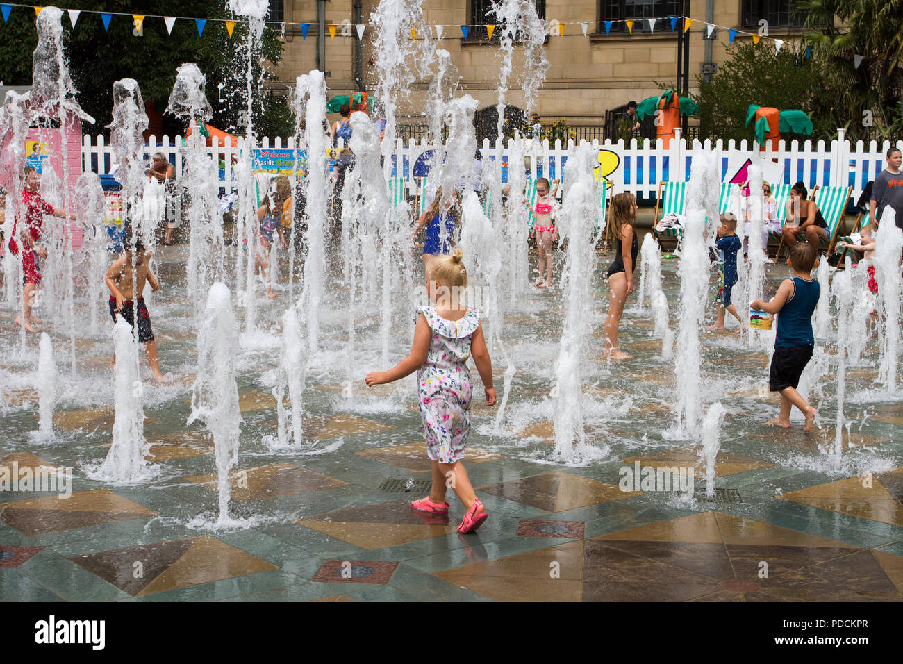 In a Sheffield park in Yorkshire, children play in water jet fountains ...