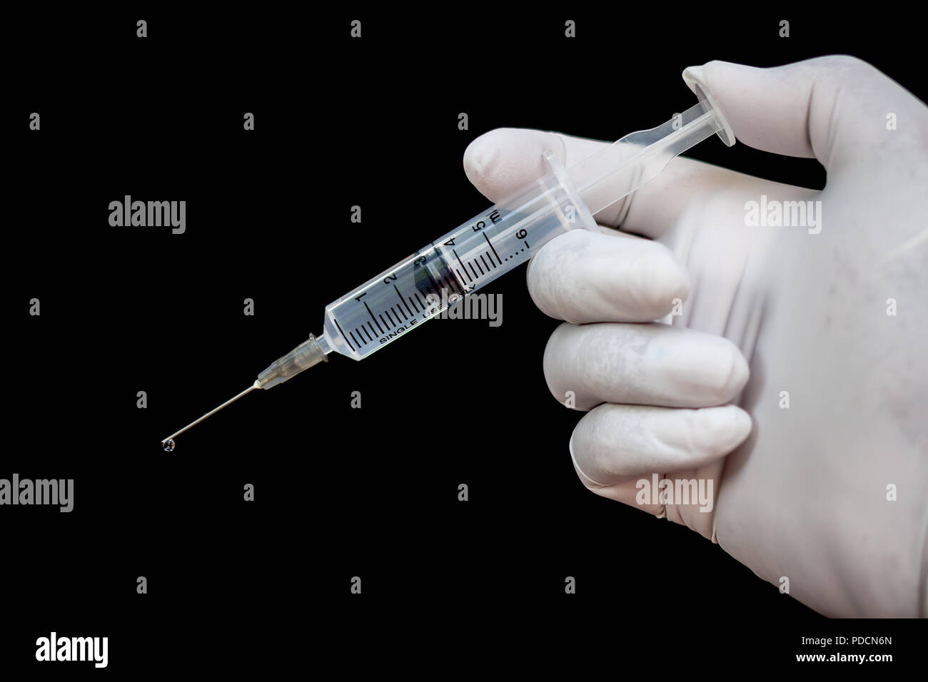 Syringe in a hand in medical gloves, ready for injection with ...