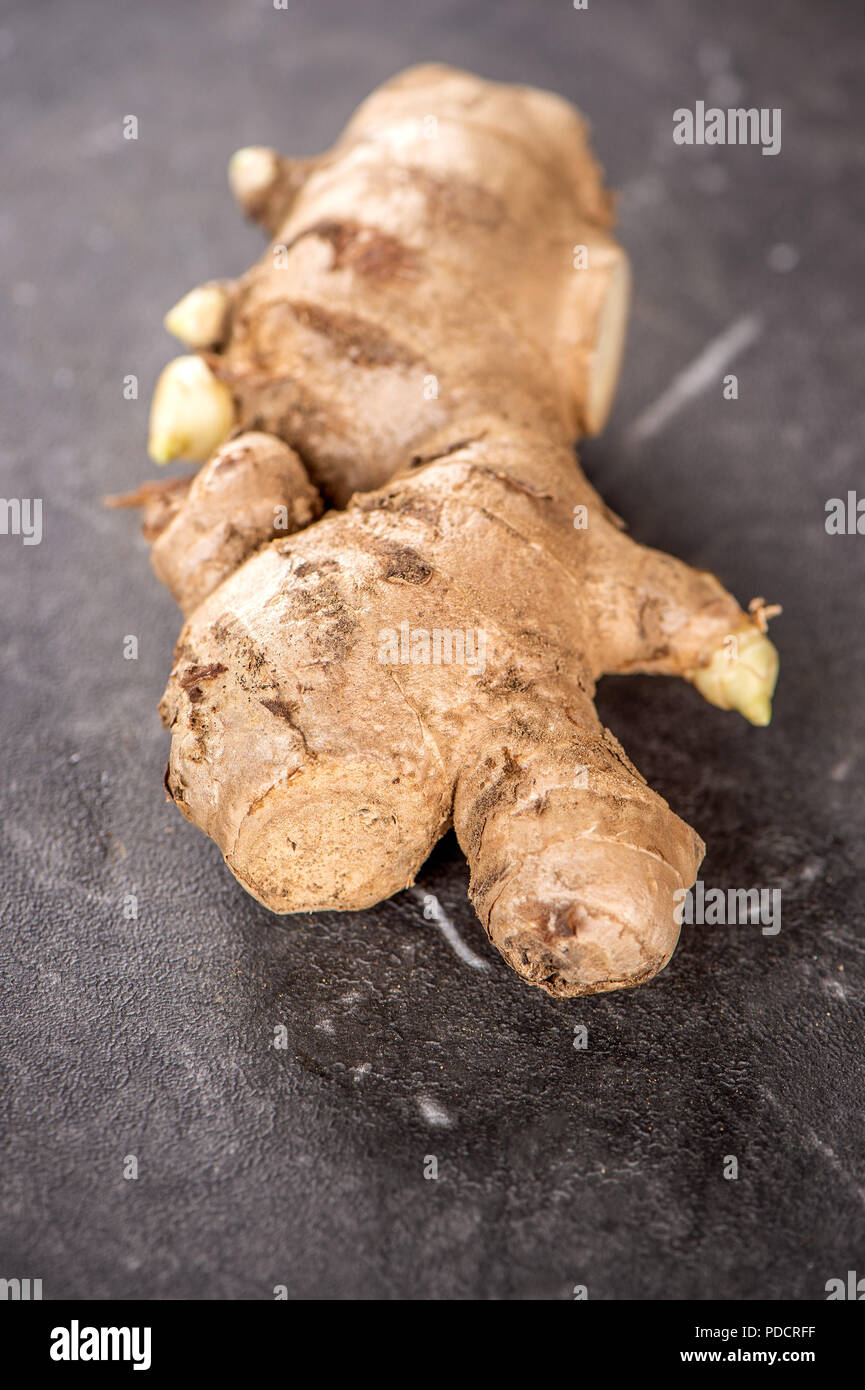 Whole ginger roots on dark old stone background table, space for text ...