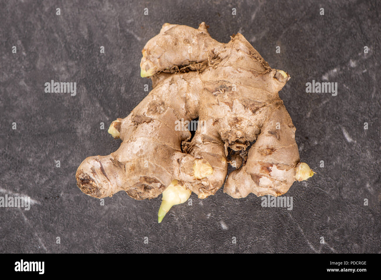 Whole ginger roots on dark old stone background table, space for text ...