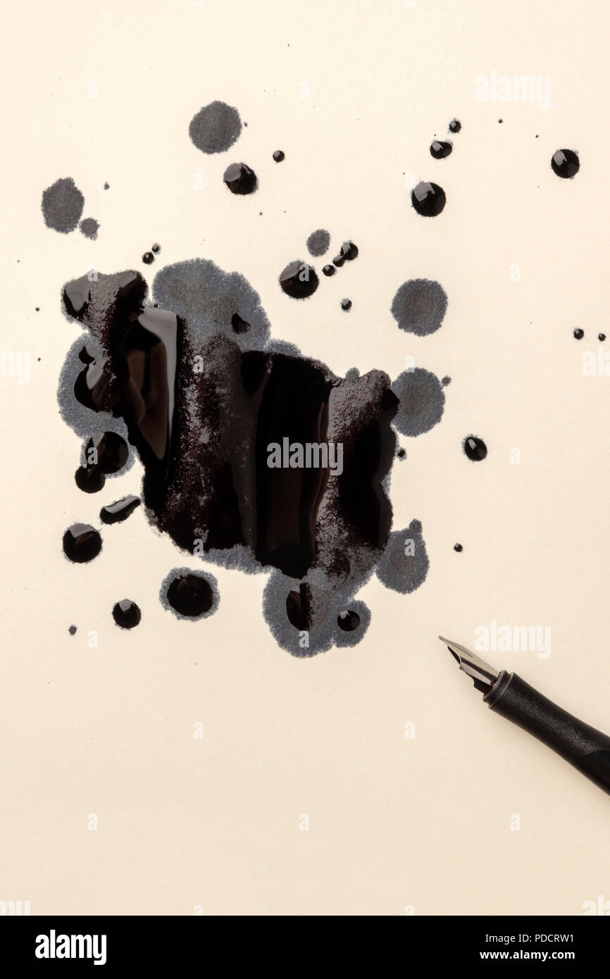 An overhead closeup photo of drops of ink on a textured off-white paper ...