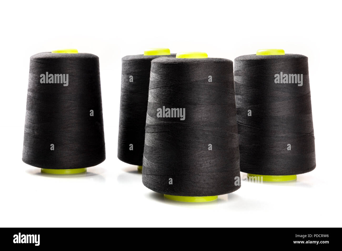 A side view of large black thread spools on a white background with ...