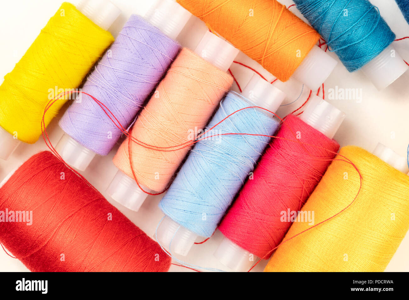 An overhead closeup photo of vibrant sewing thread spools in different ...