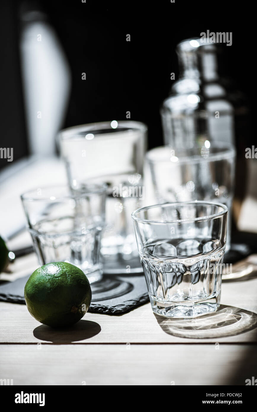 close-up view of fresh lime and empty glasses with shaker, selective ...