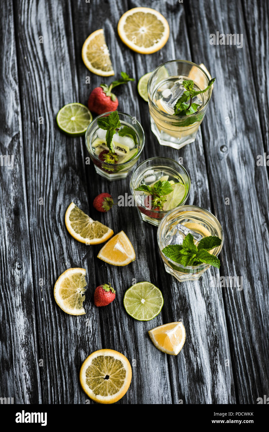 top view of fresh cold summer cocktails in glasses on wooden table ...