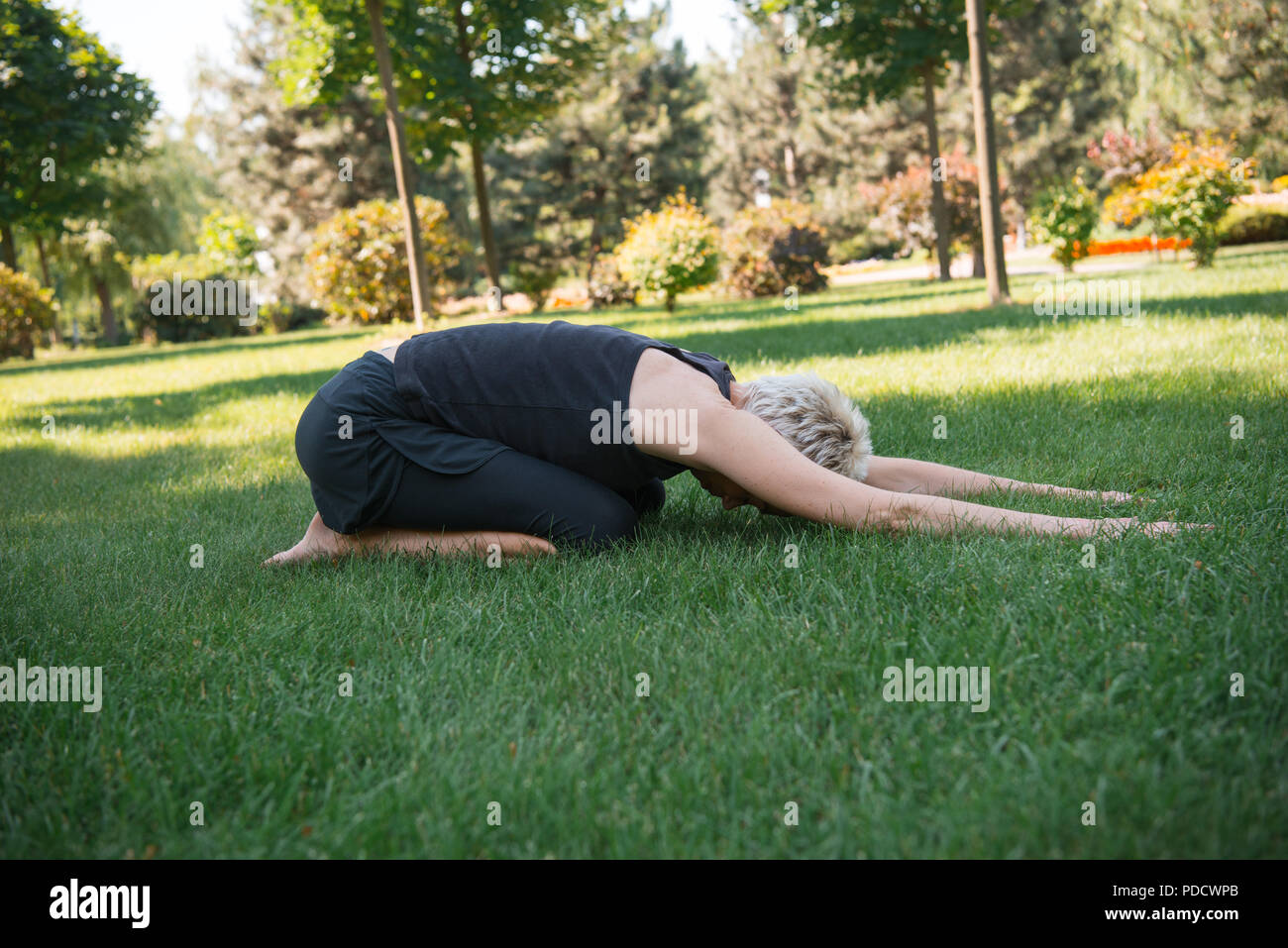 side view of woman practicing yoga in Extended Child pose (Utthita ...