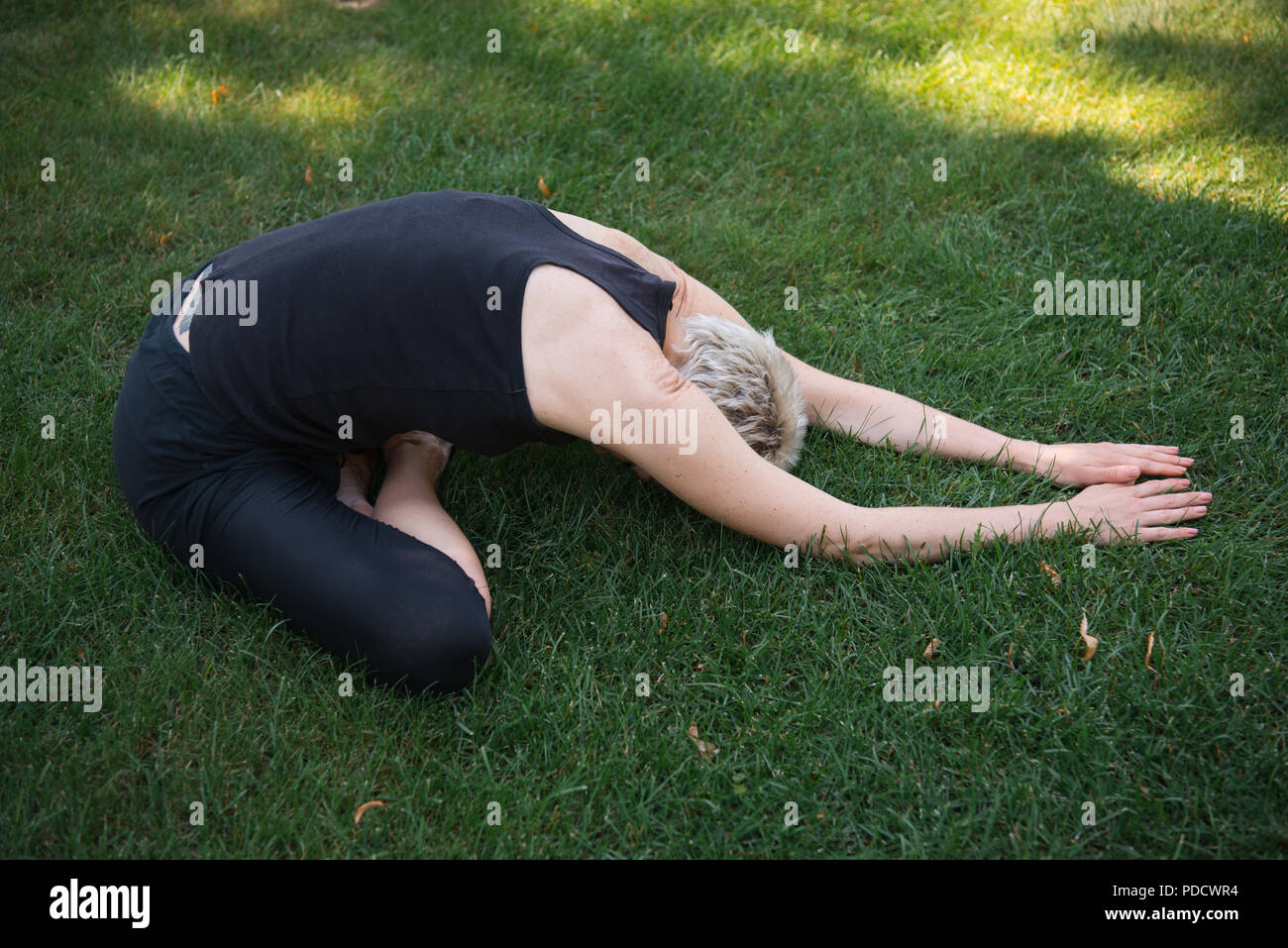 side view of woman practicing yoga in Wide Child pose (Balasana) on ...