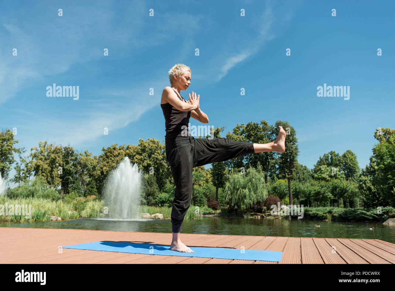 side view of woman practicing yoga on yoga mat and making namaste ...