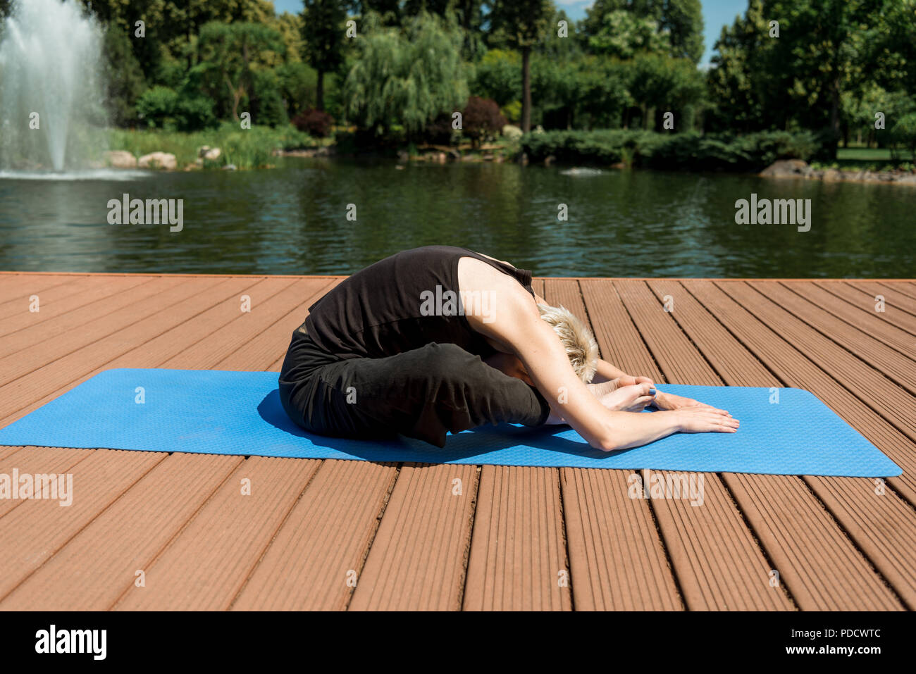 side view of woman practicing yoga in Wide Child pose (Balasana) on ...
