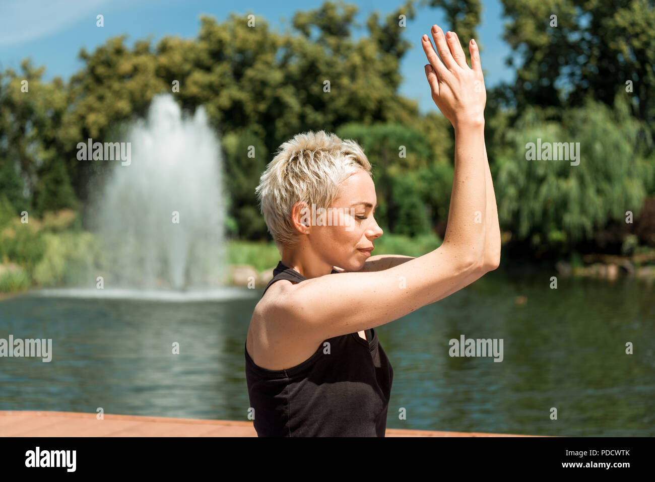 side view of woman practicing yoga with hands in namaste gesture near ...