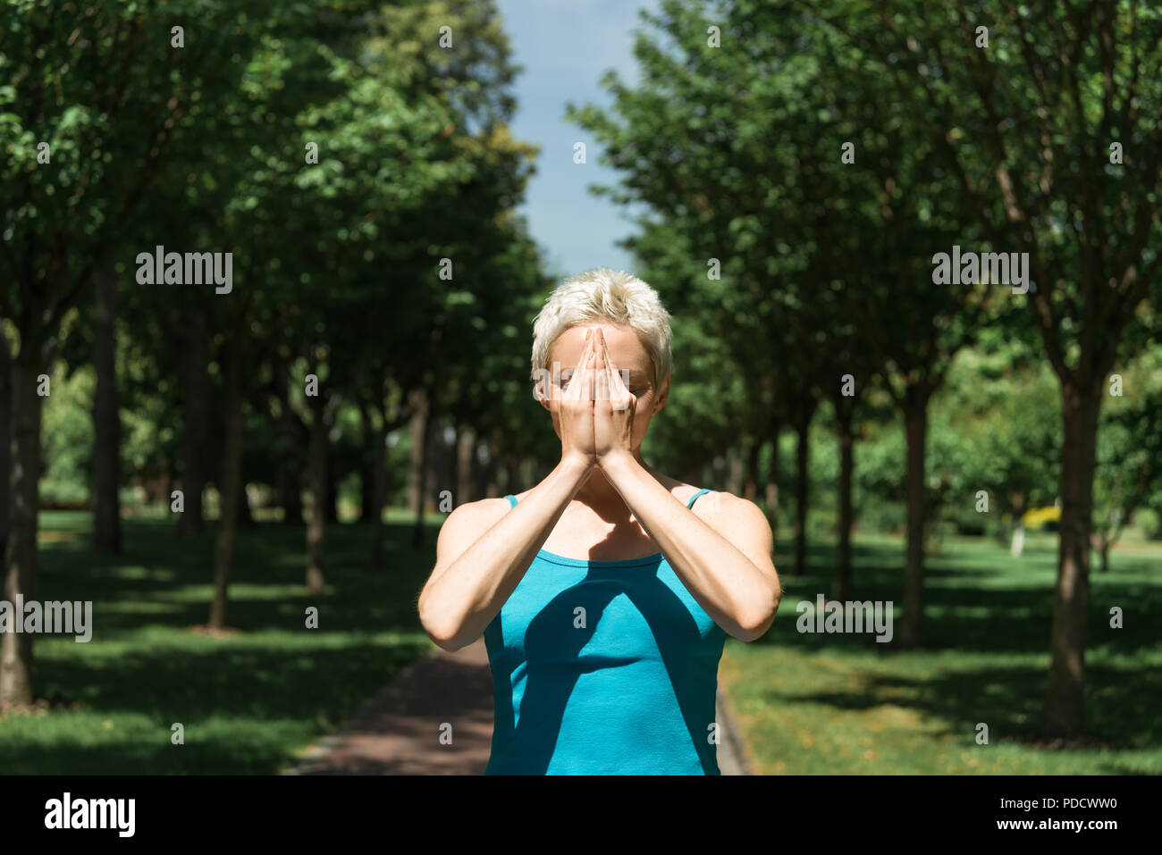 woman practicing yoga and standing with hands in namaste gesture in ...