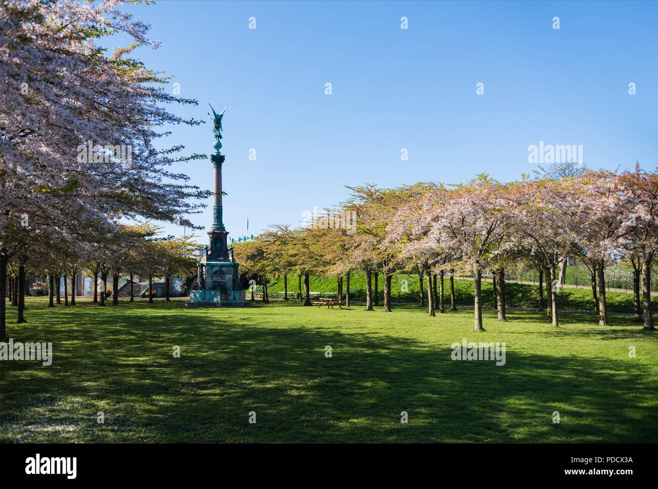 monument between beautiful blooming trees in park, copenhagen, denmark ...