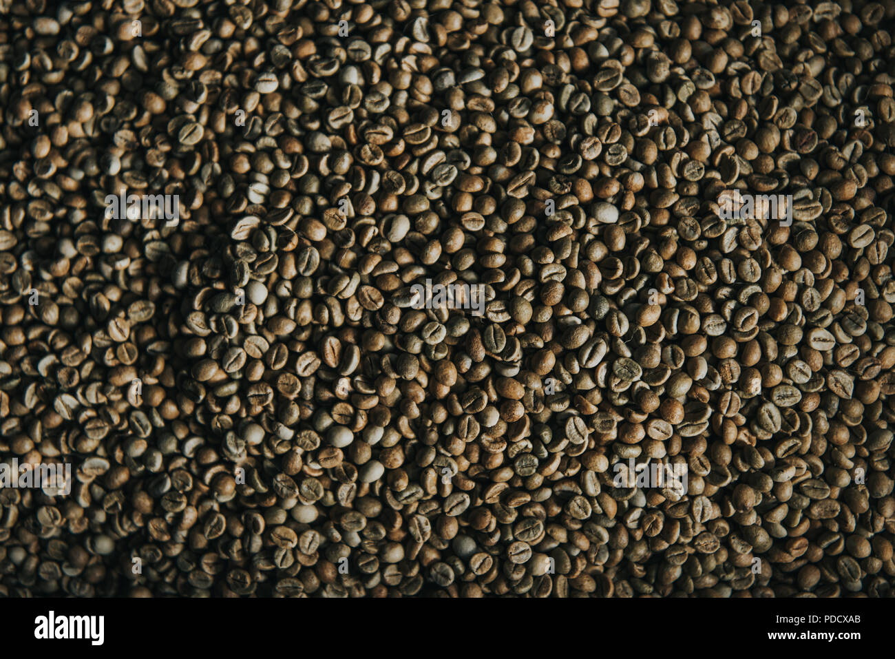 Raw coffee beans in process of roasting texture Stock Photo - Alamy