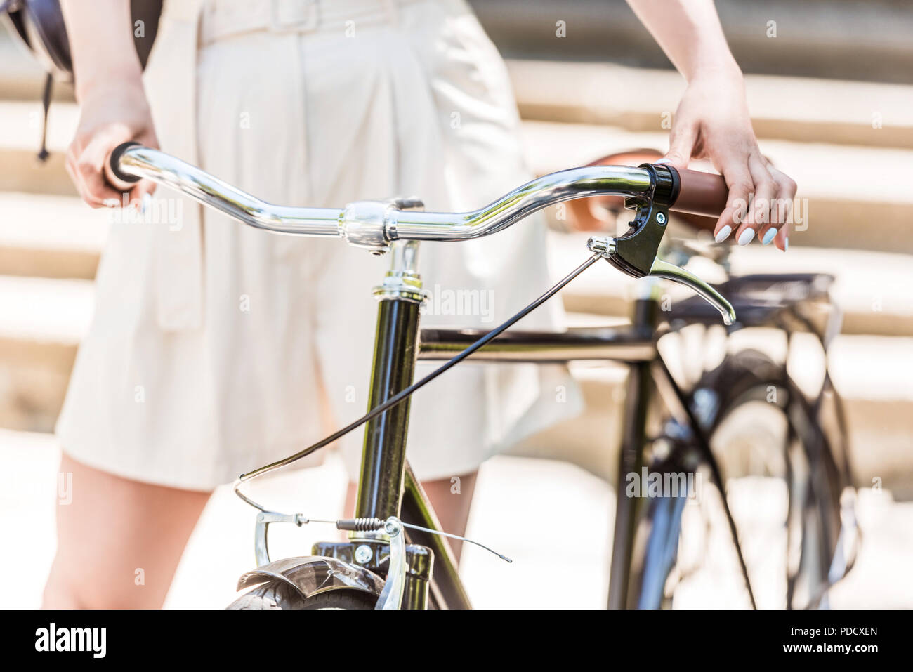 cropped shot of woman holding handlebar of retro bicycle on street ...