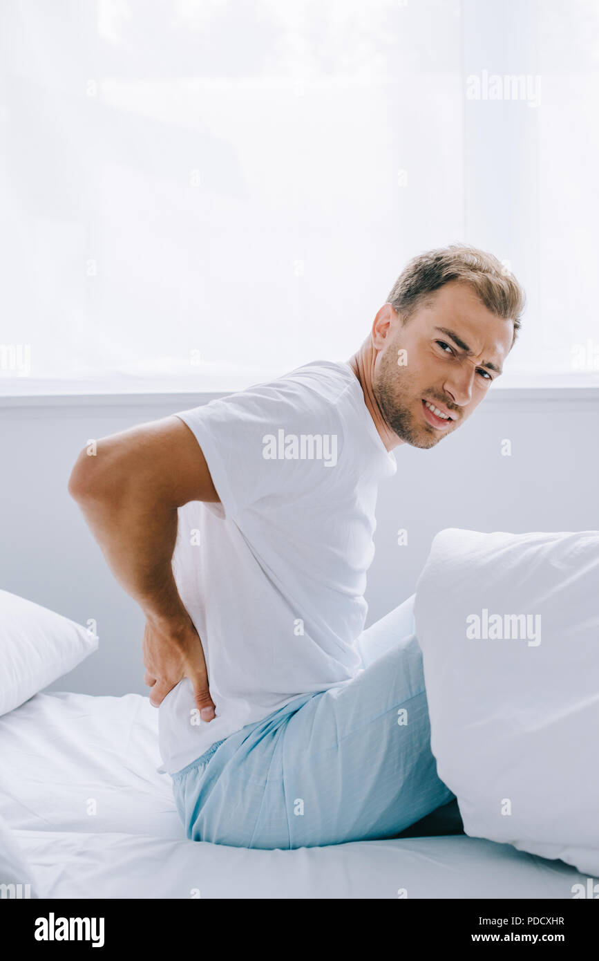 side view of man suffering from back pain and looking at camera in ...