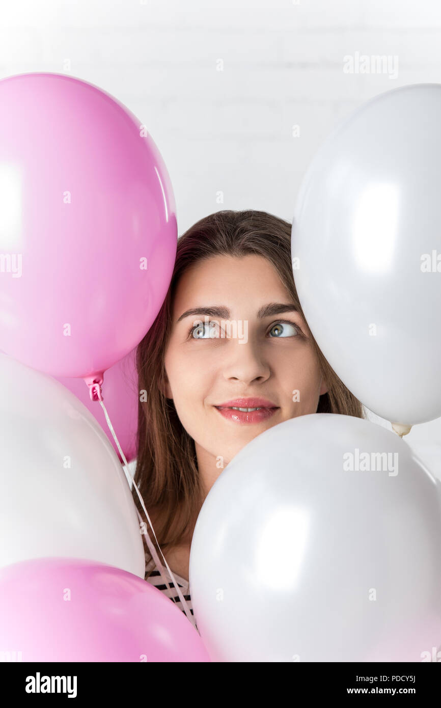 Smiling girl among balloons on white brick wall background Stock Photo ...