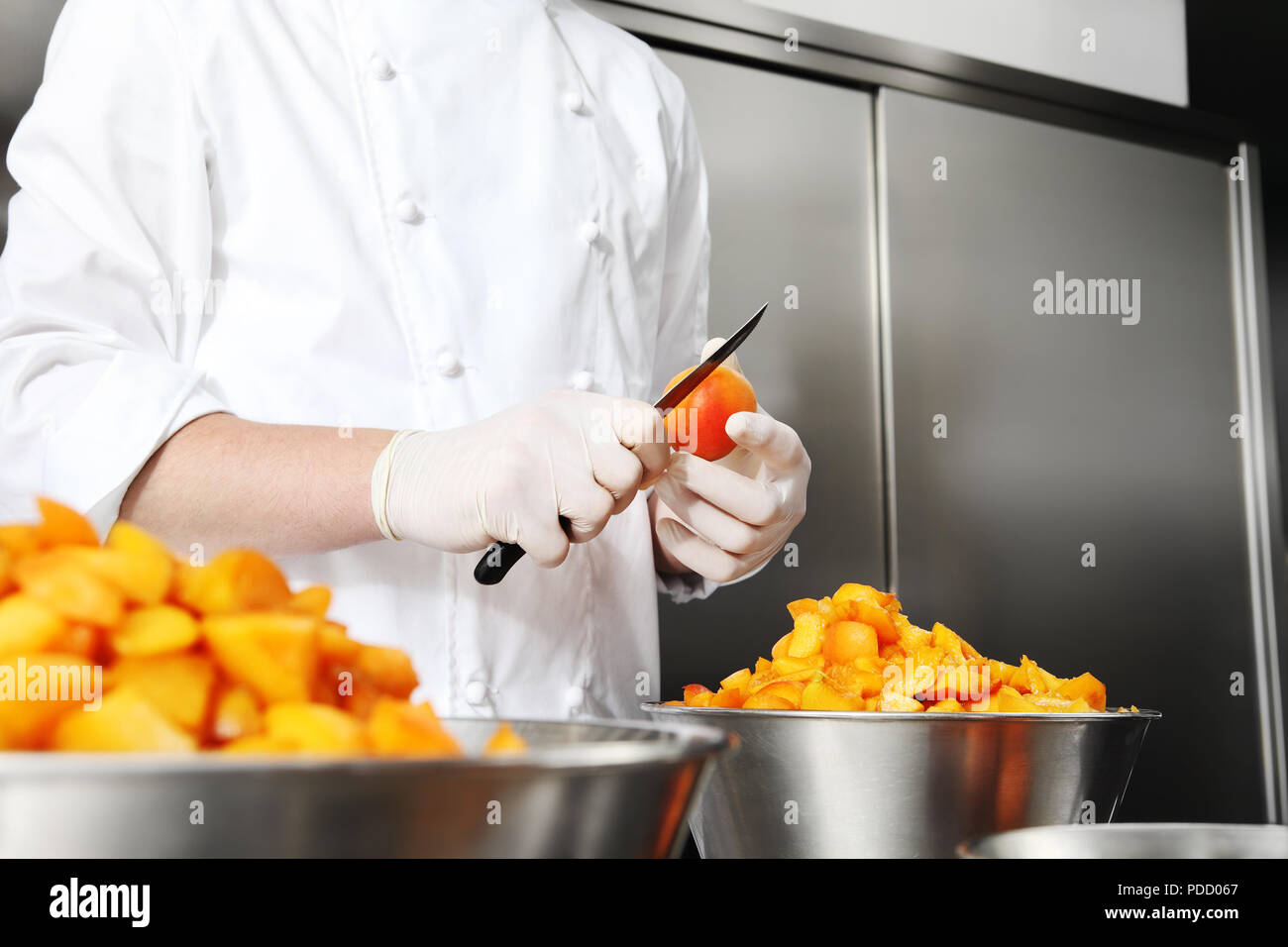 hands pastry chef cutting apricots, prepare the jam in industrial ...