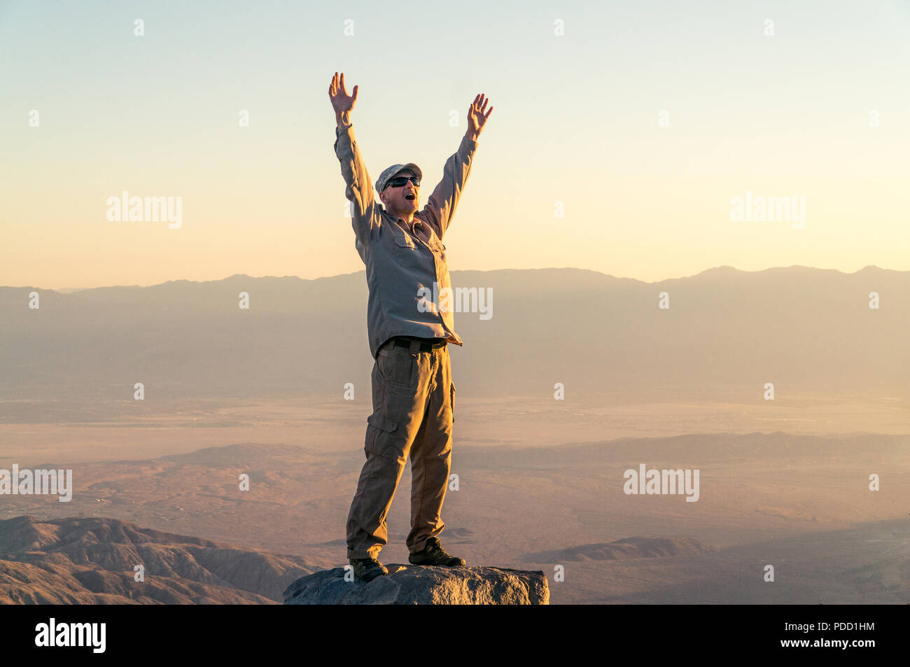 Tourist at the summit with raised hands in the Joshua Tree National ...