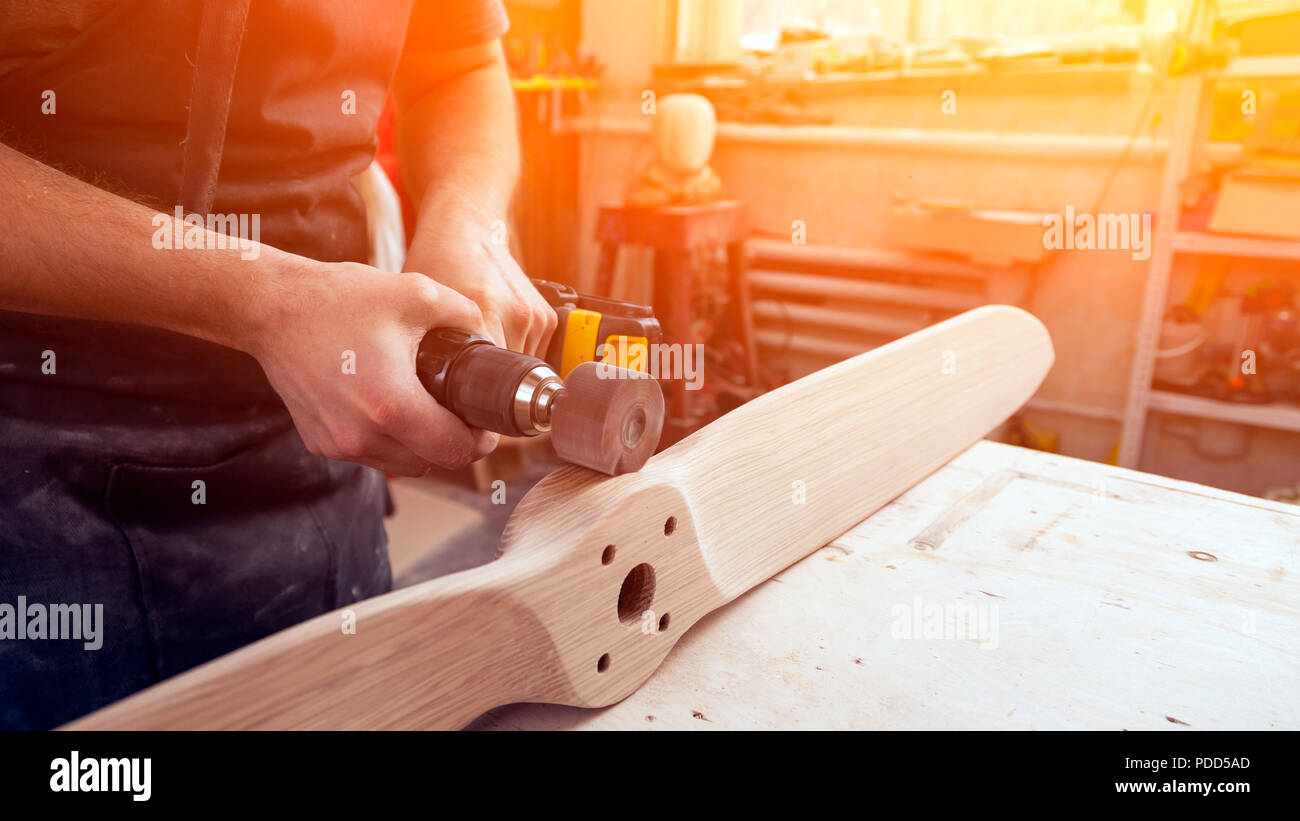 Close up of an young man builder carpenter equals polishes wooden board ...