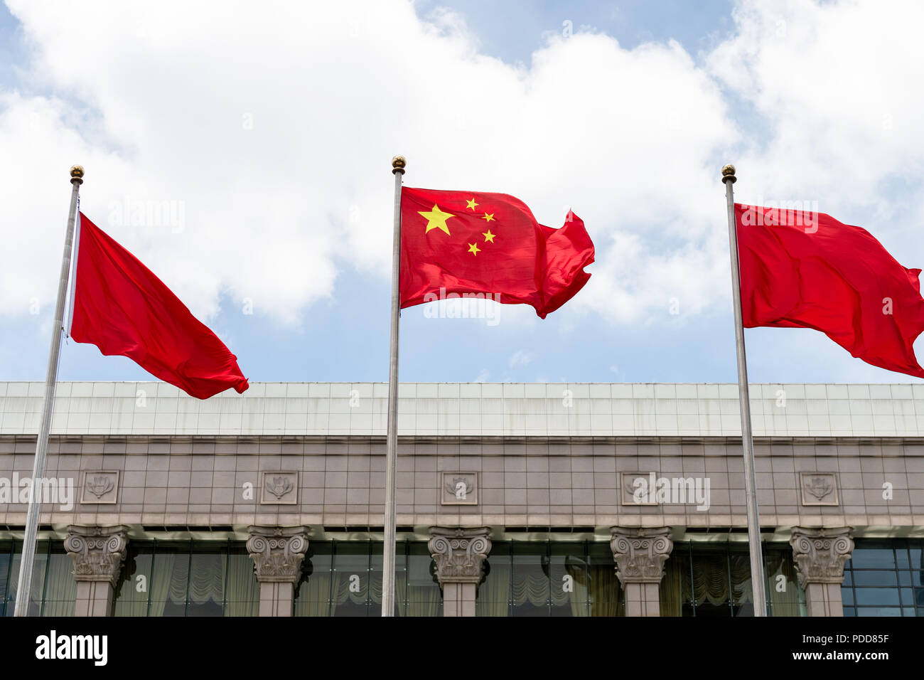 Chinese national flag flying from a pole with building roof in ...