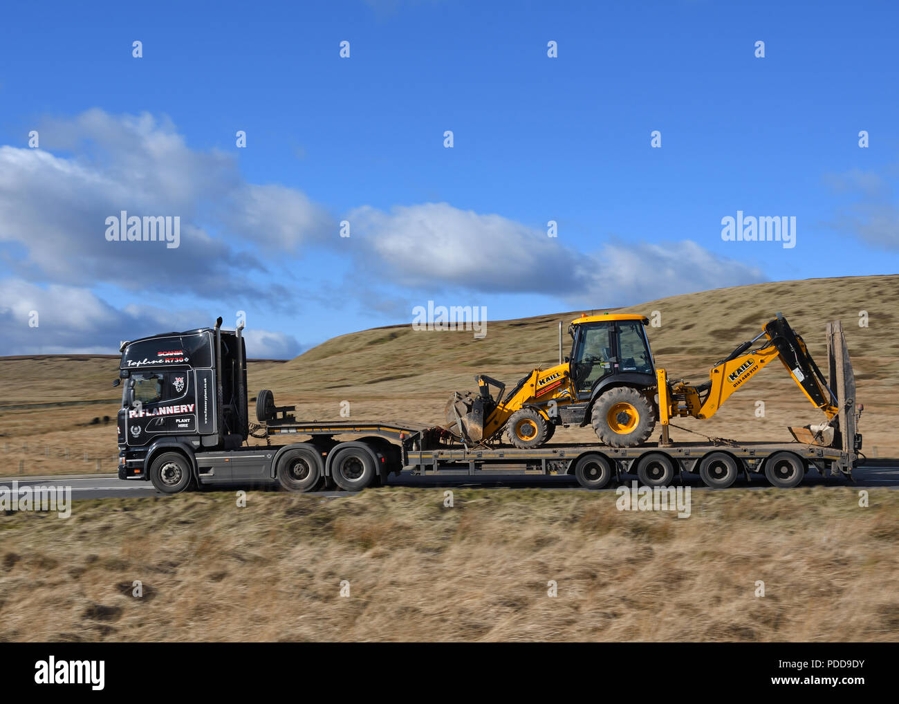 Scania towing low-loader trailer transporting a back hoe-equipped ...