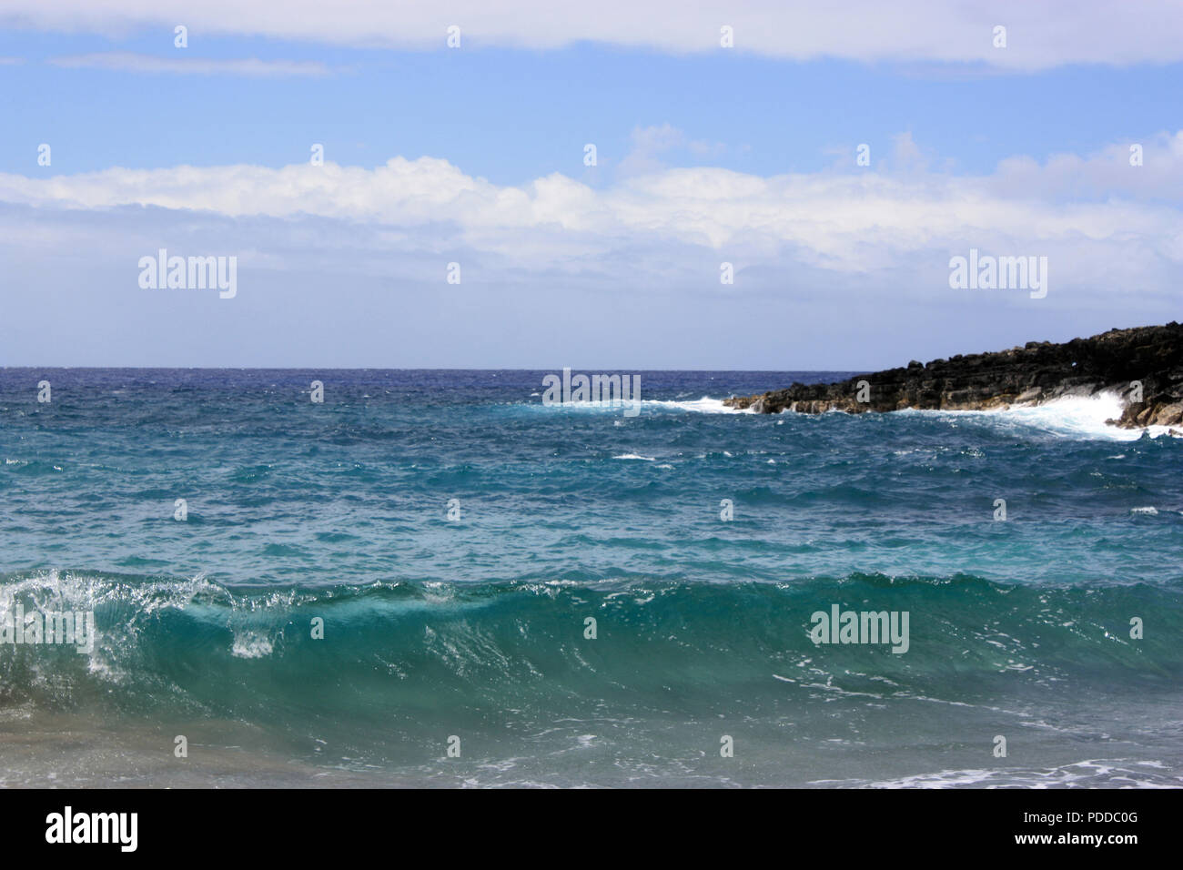A wave consisting of multiple shades of blue ocean water in a bay in ...