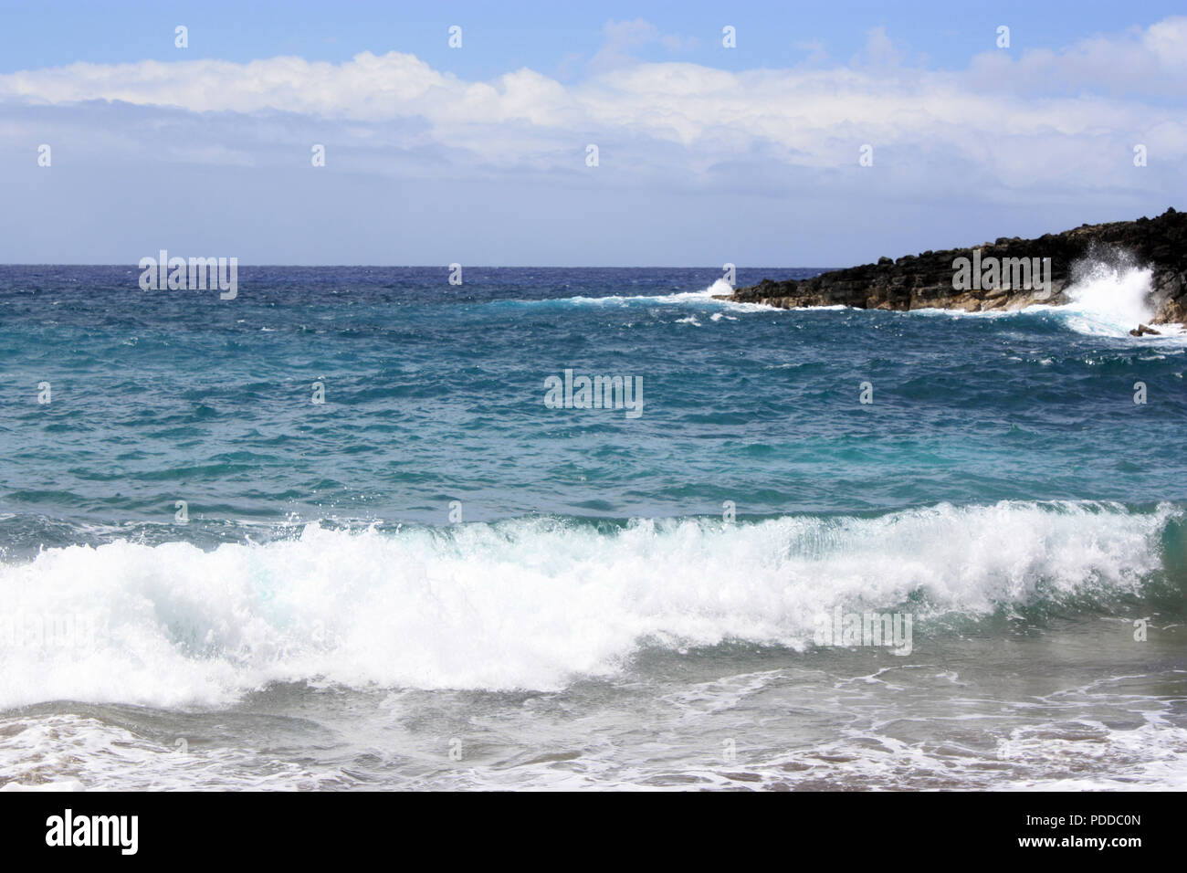A wave consisting of multiple shades of blue ocean water in a bay in ...