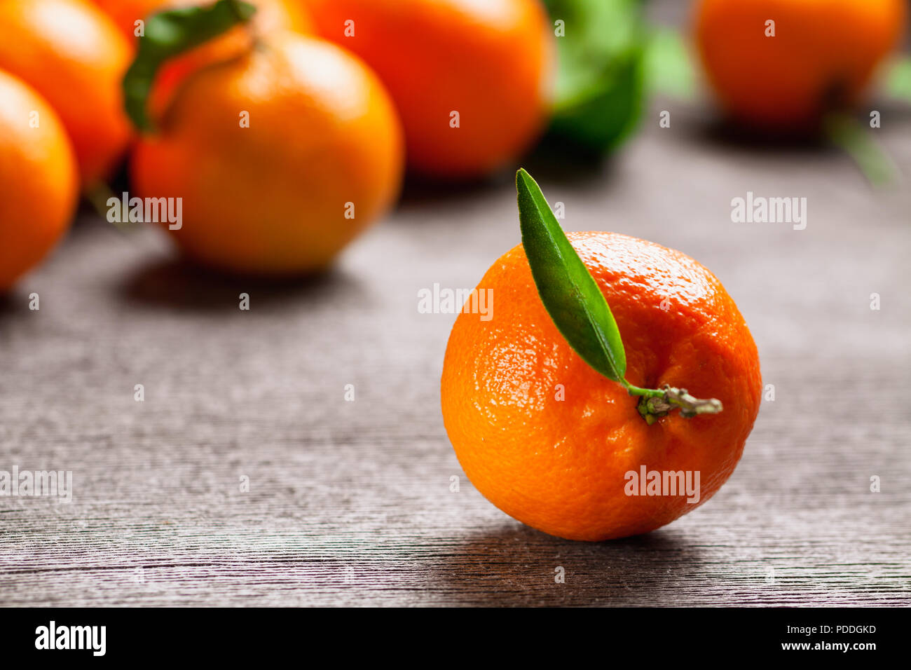 Single mandarin in juicy orange colour with green leaf is laying before ...