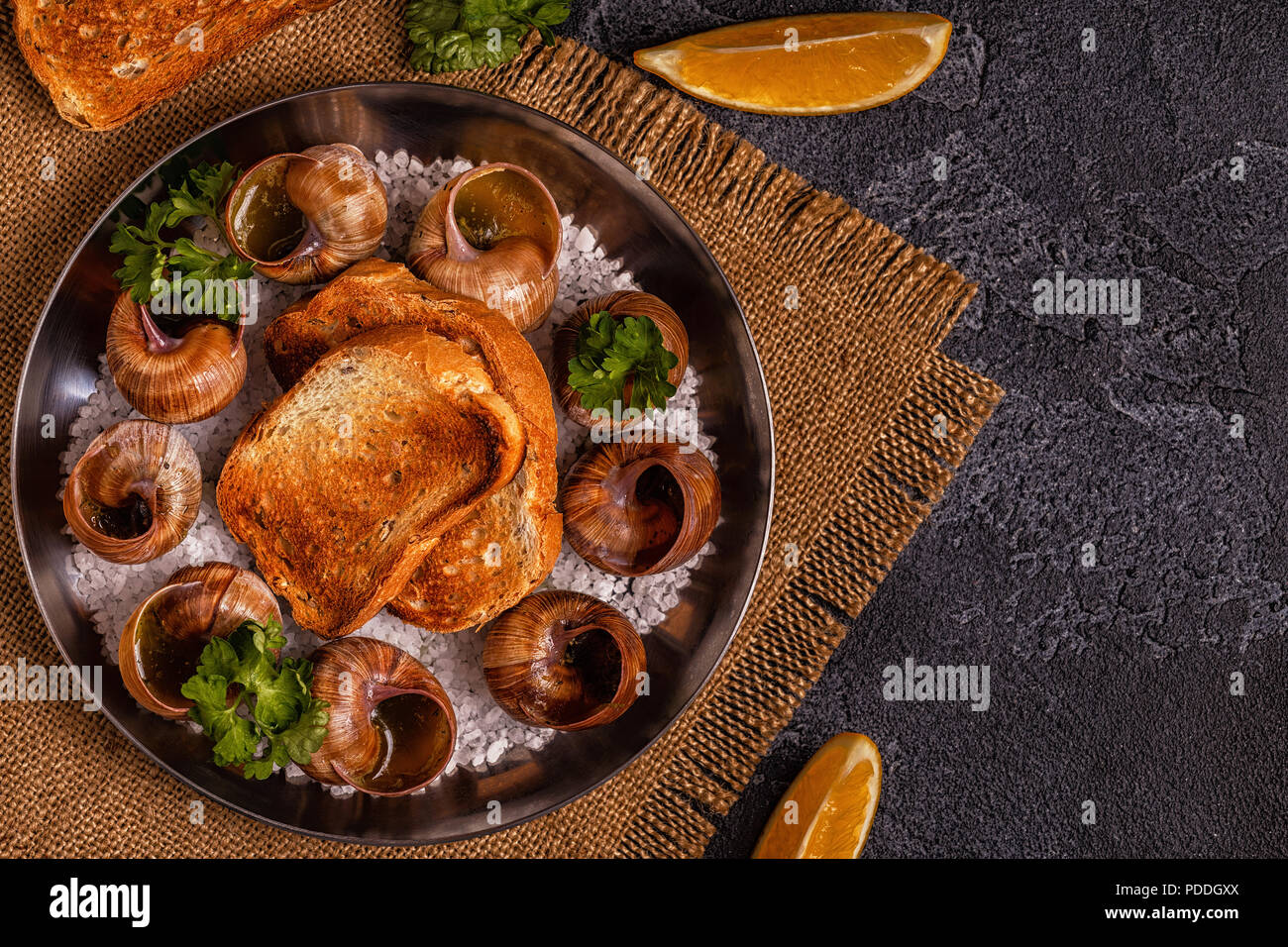 Fried snails with lemon, baguette and parsley, top view Stock Photo - Alamy
