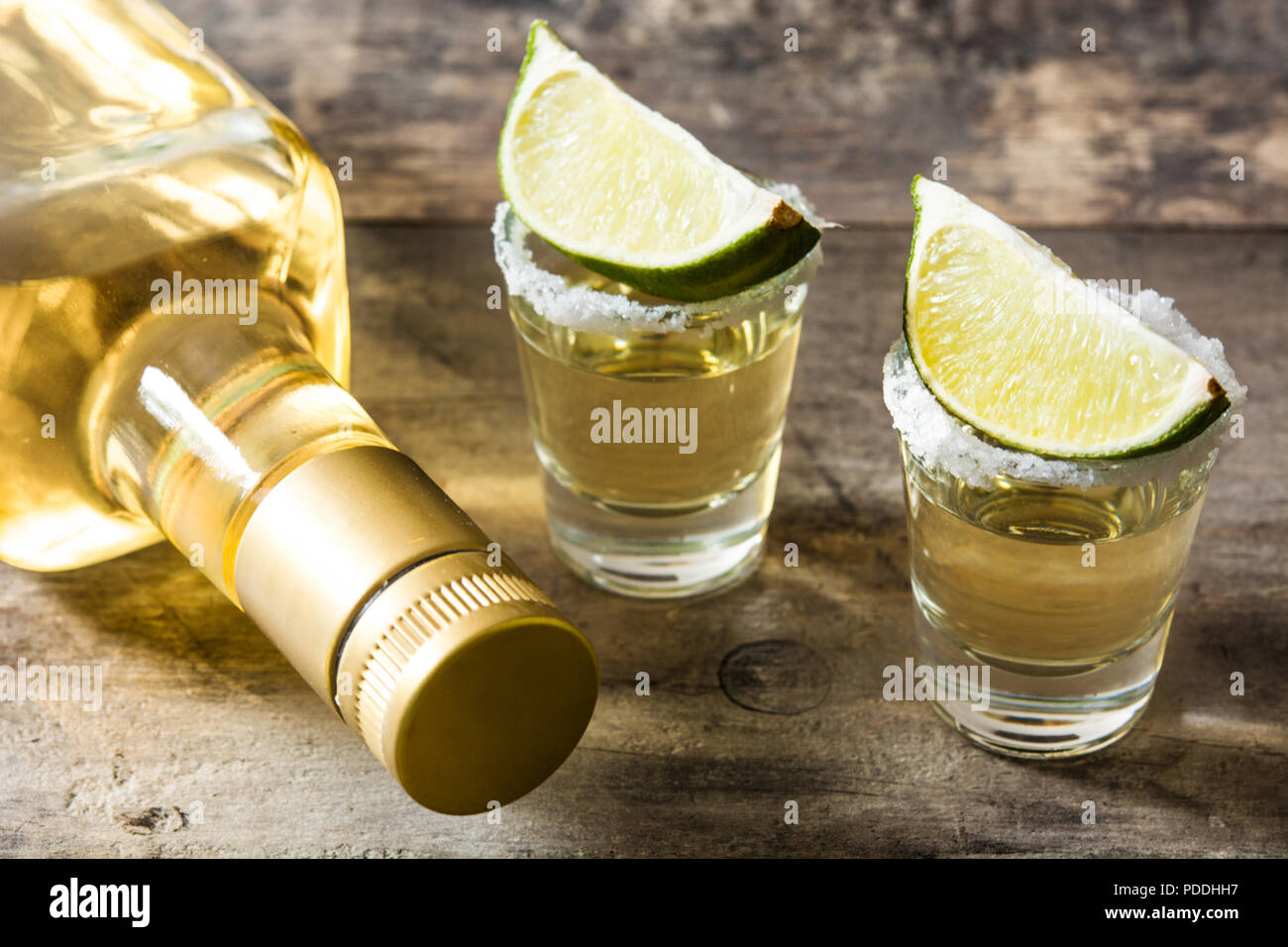 Mexican Gold tequila with lime and salt on wooden table Stock Photo - Alamy