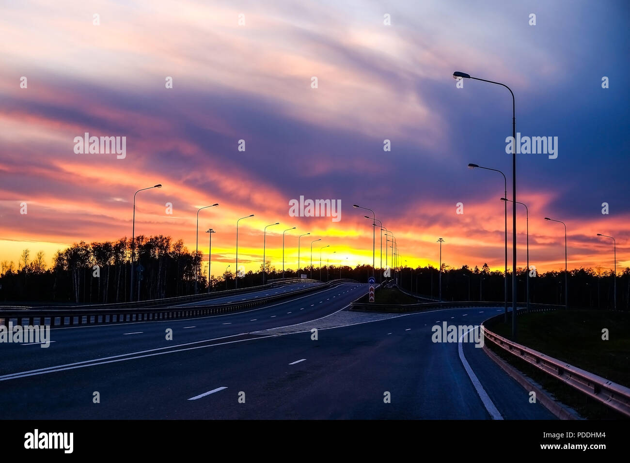 Interchange of the highway. Dramatic sky, fiery sunset. The lights on ...