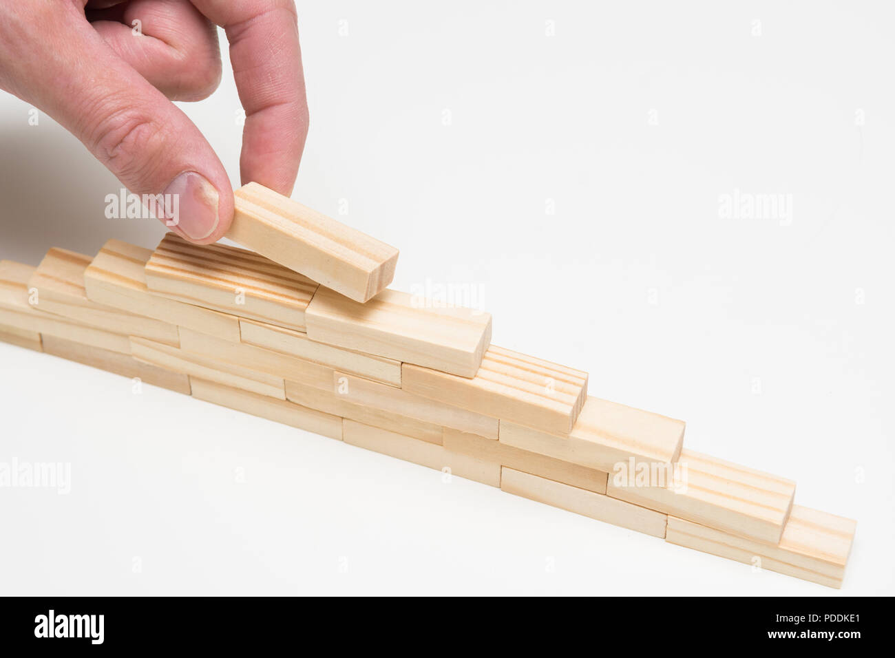 Hand adding final piece to block tower. Business solutions and problem ...